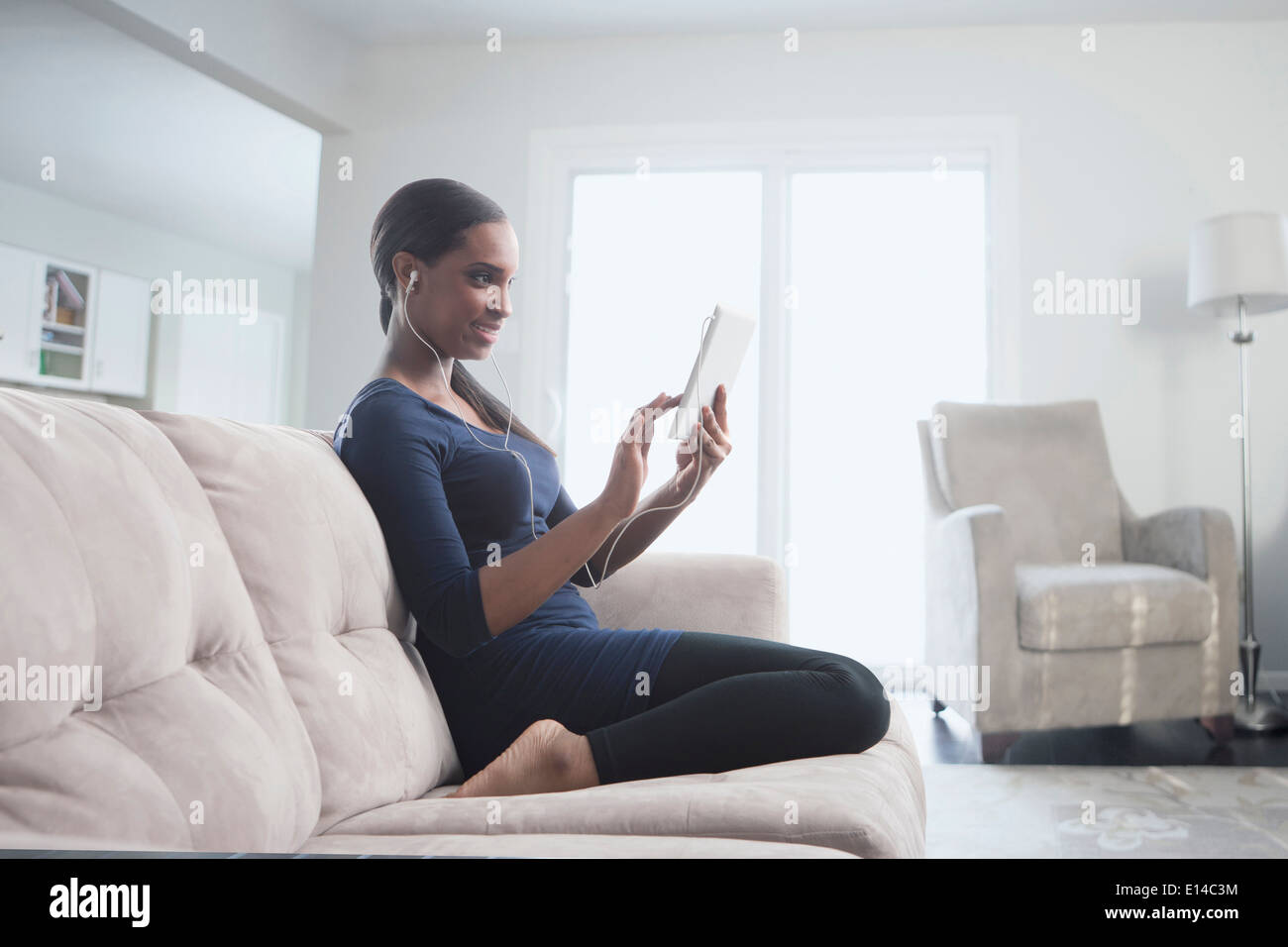 Black woman using digital tablet on sofa Stock Photo - Alamy