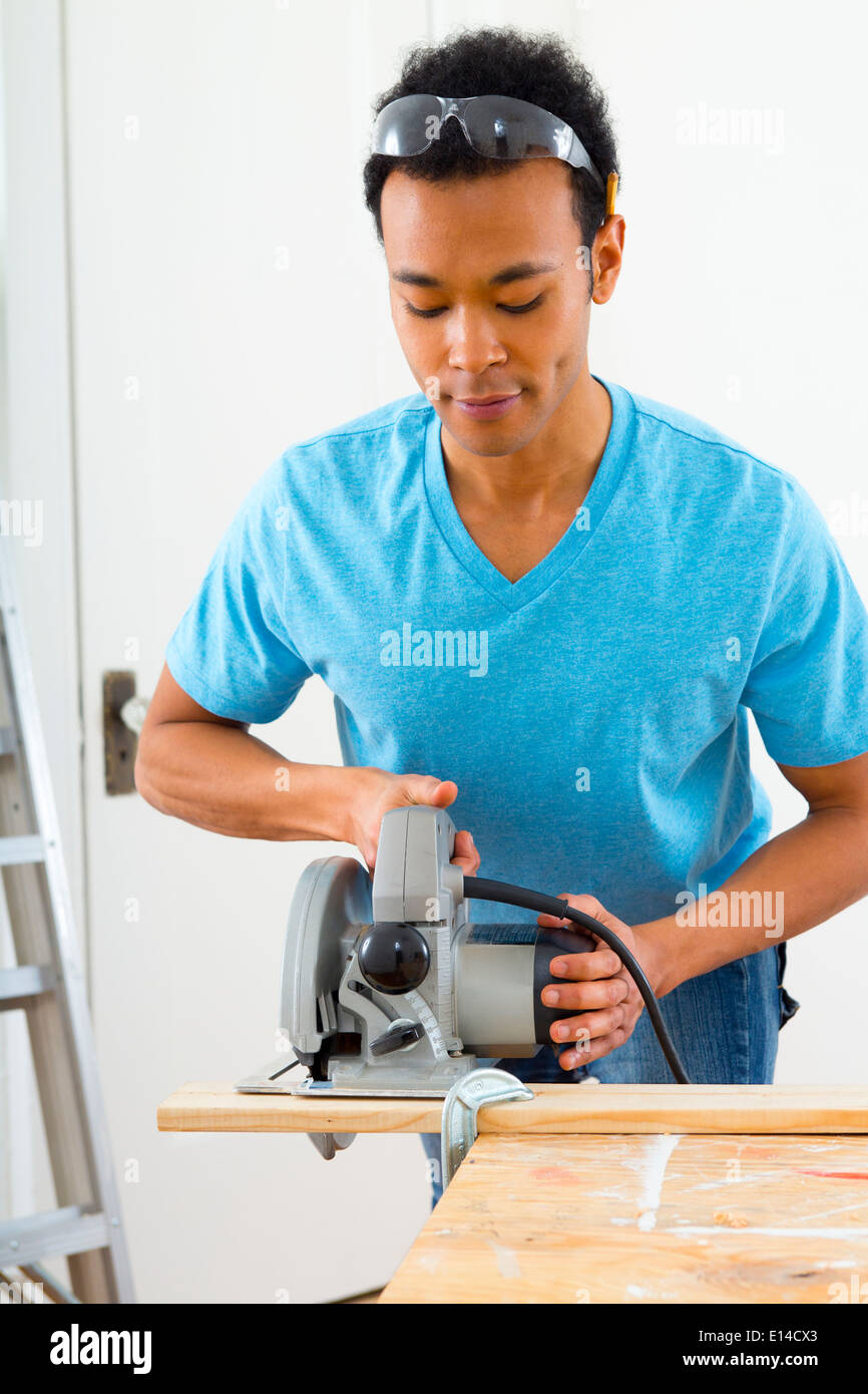Mixed race carpenter using hand saw Stock Photo - Alamy