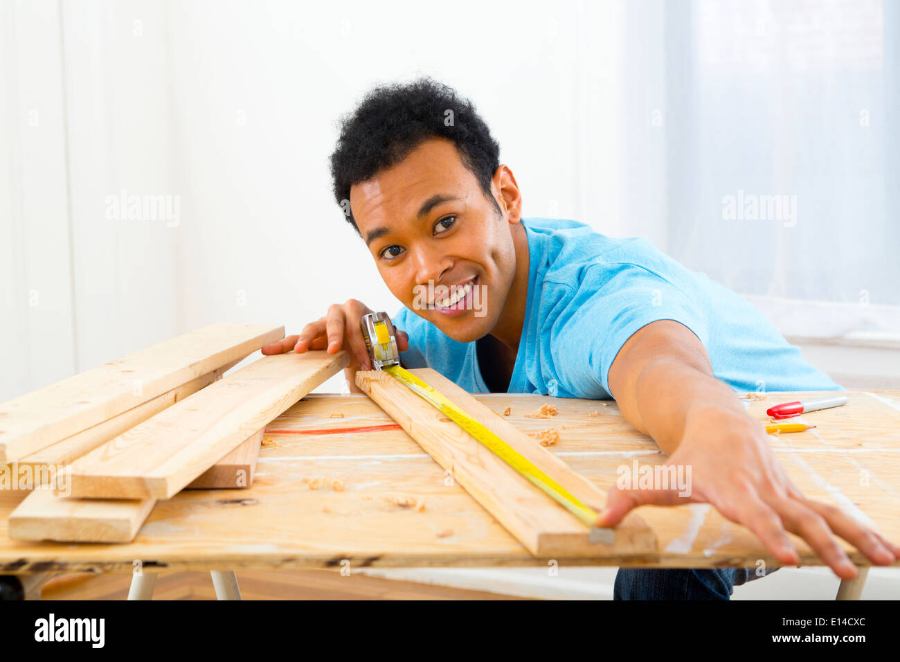 Mixed race carpenter measuring wood with tape measure Stock Photo - Alamy
