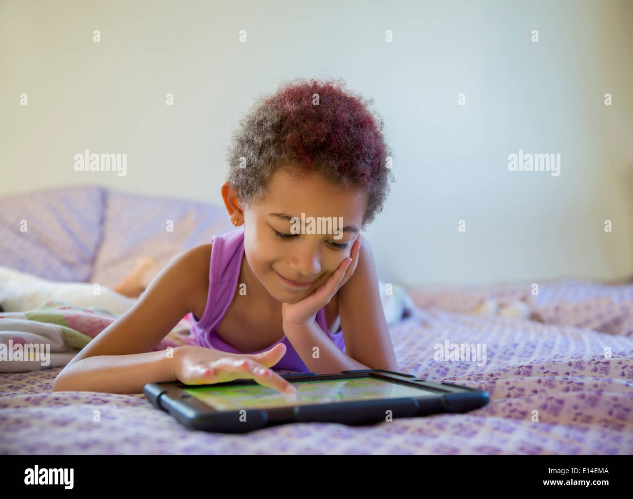 Mixed race girl using digital tablet in bed Stock Photo - Alamy