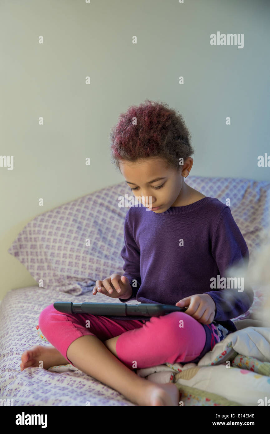 Mixed race girl using digital tablet in bed Stock Photo - Alamy
