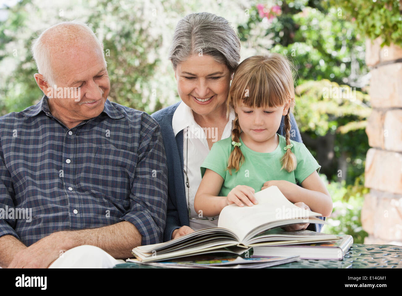 Grandparents and granddaughter reading outdoors Stock Photo - Alamy