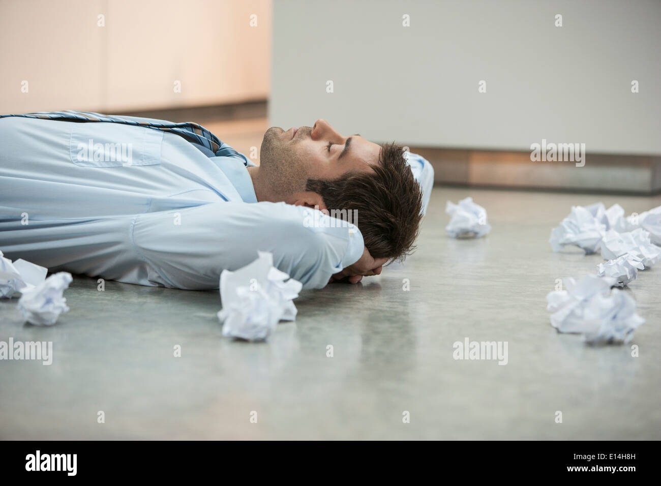 Businessman on floor surrounded by crumpled paper Stock Photo - Alamy