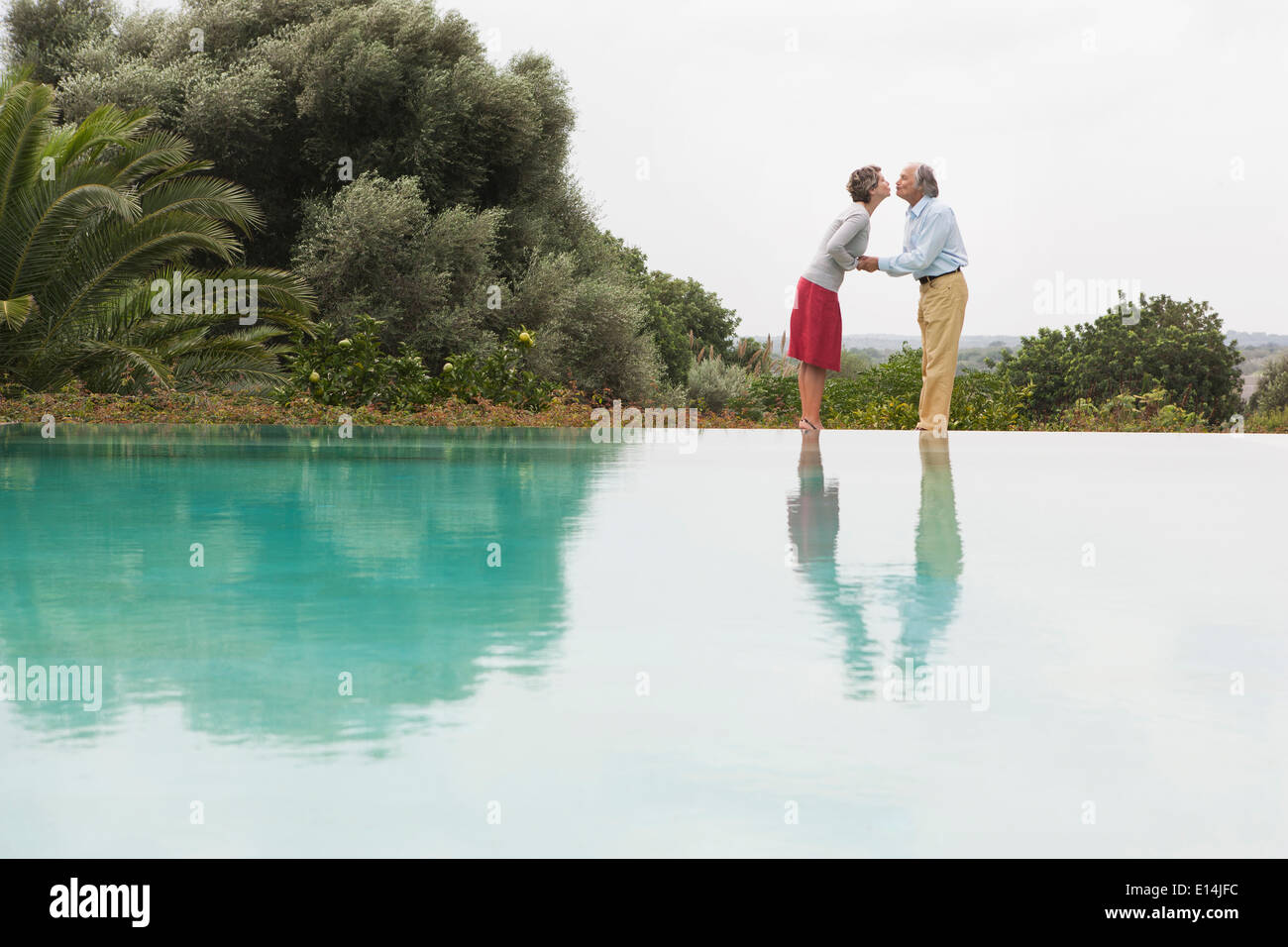 Couple kissing by infinity pool Stock Photo - Alamy