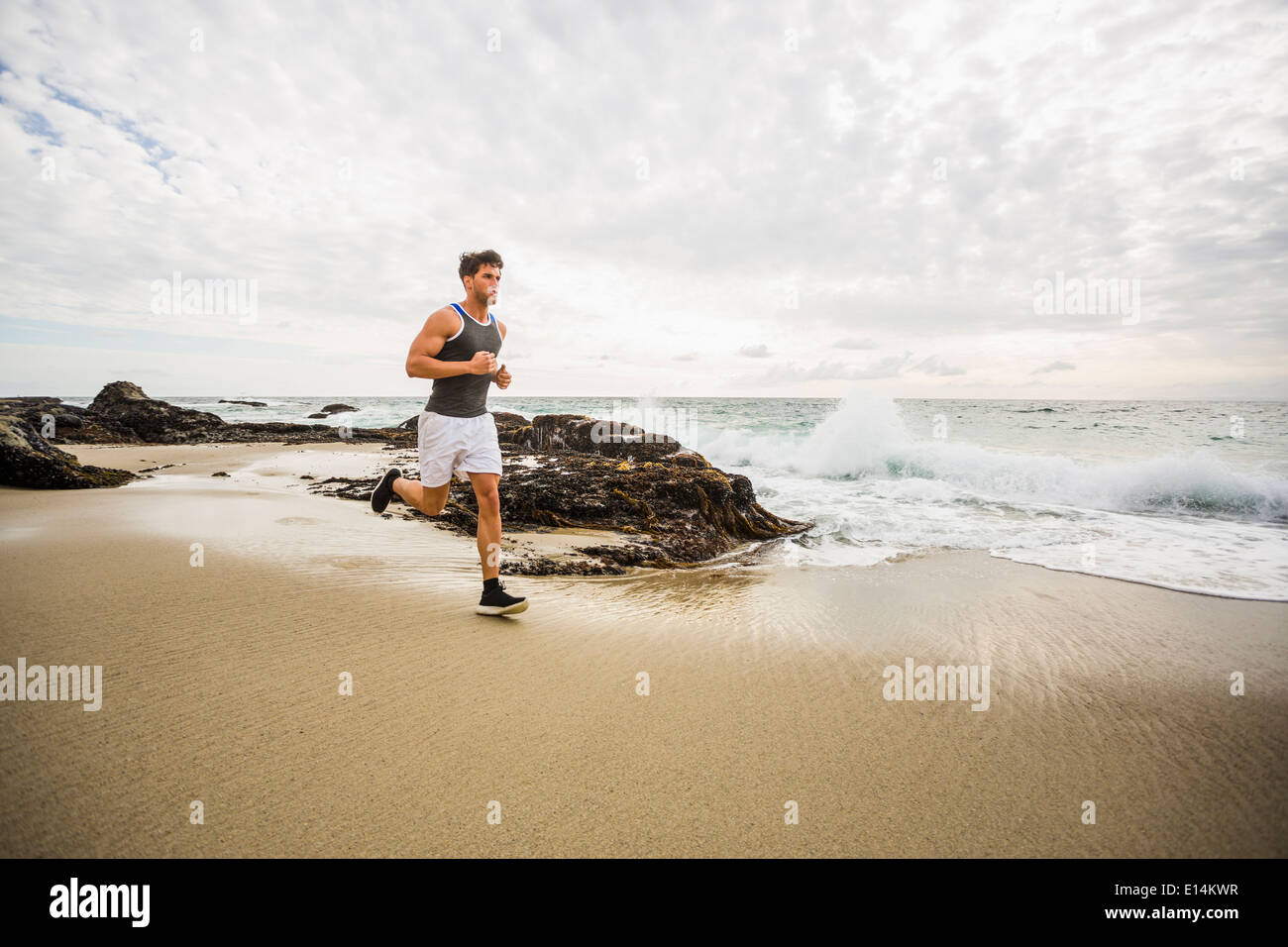 Caucasian man running on beach Stock Photo - Alamy