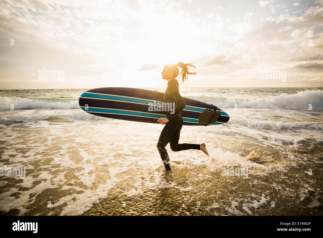Caucasian surfer carrying board in waves Stock Photo - Alamy
