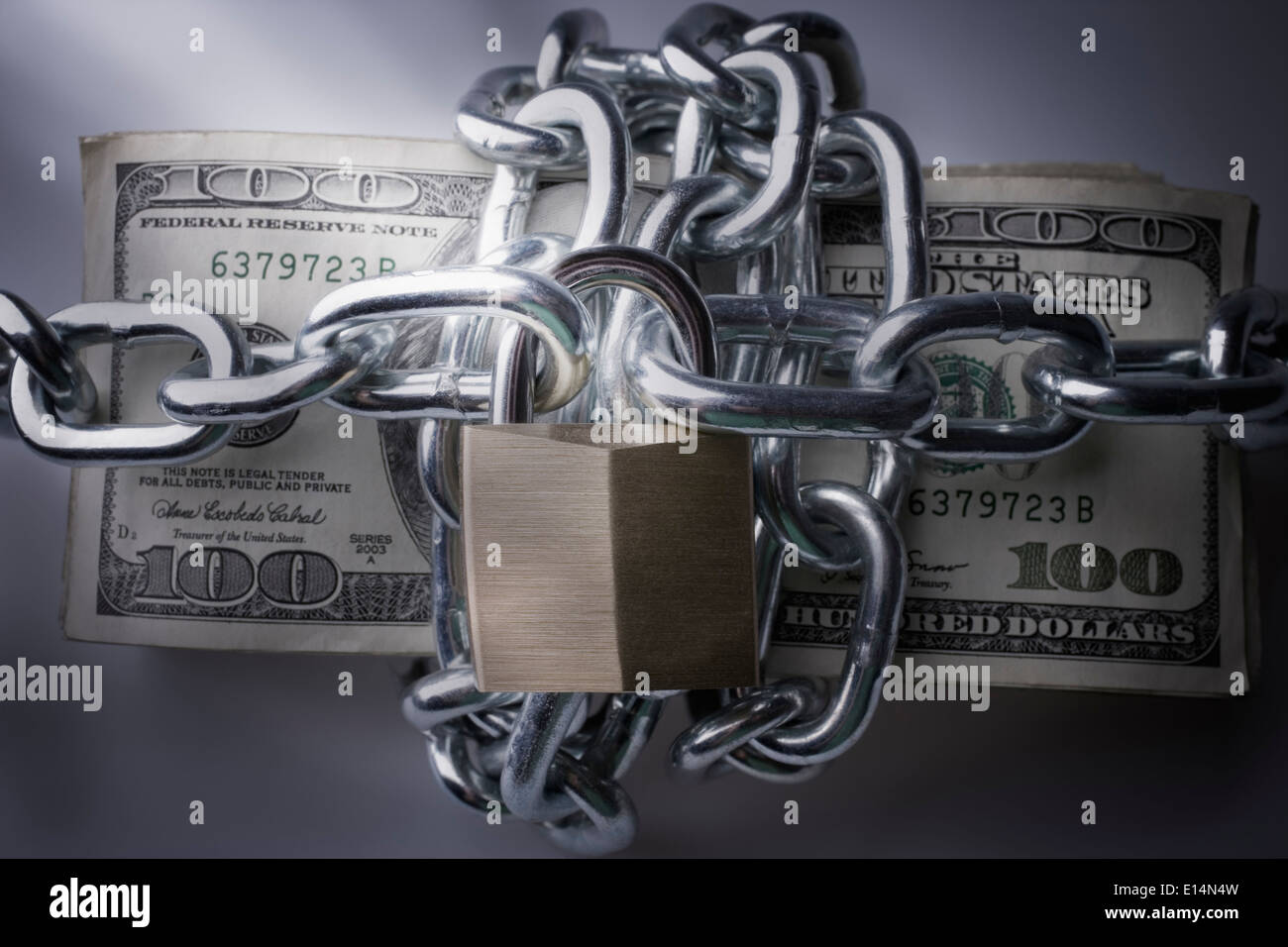 Chains and padlock around stack of dollar bills Stock Photo - Alamy