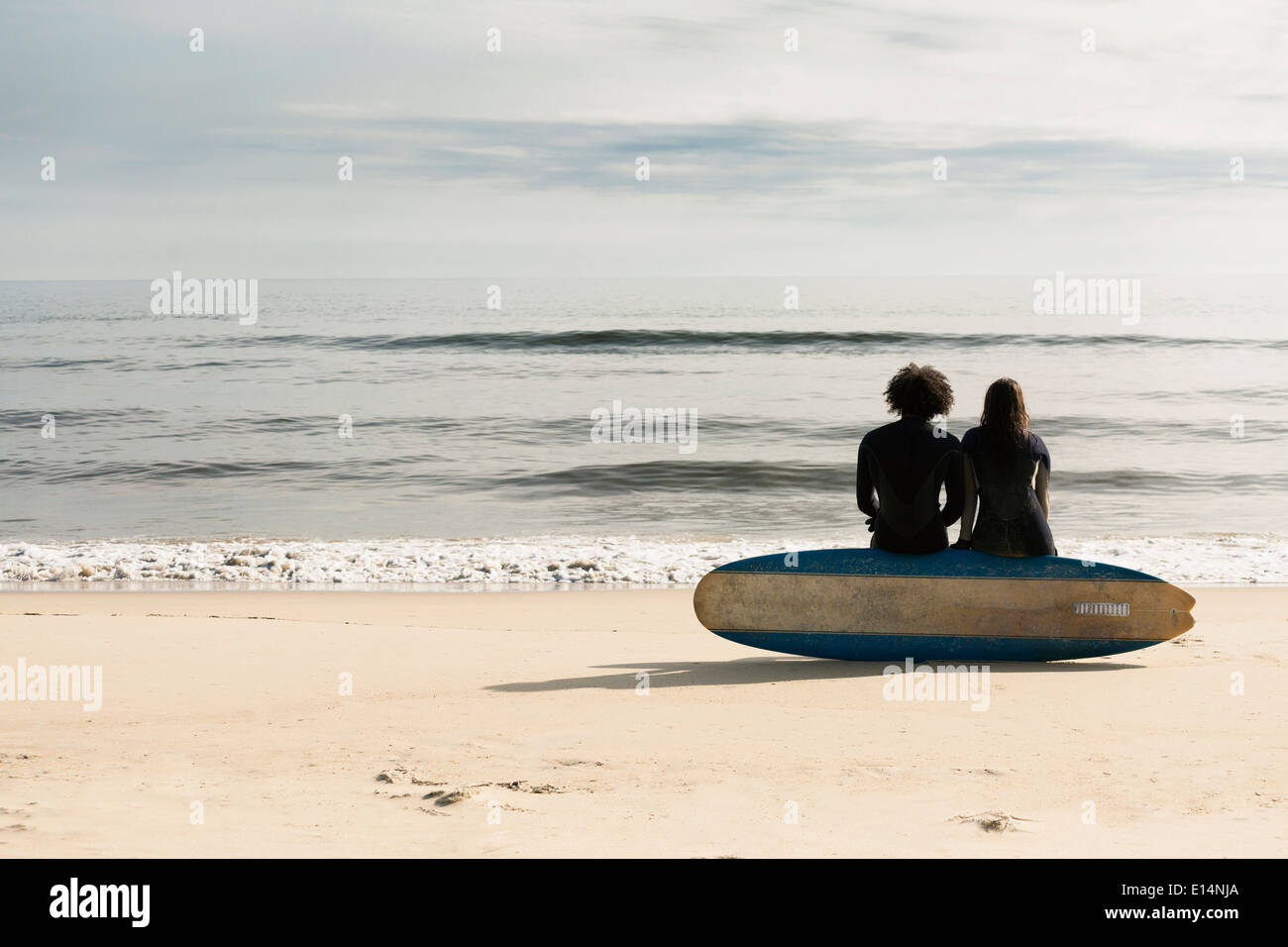 Surfers sitting on board on beach Stock Photo - Alamy