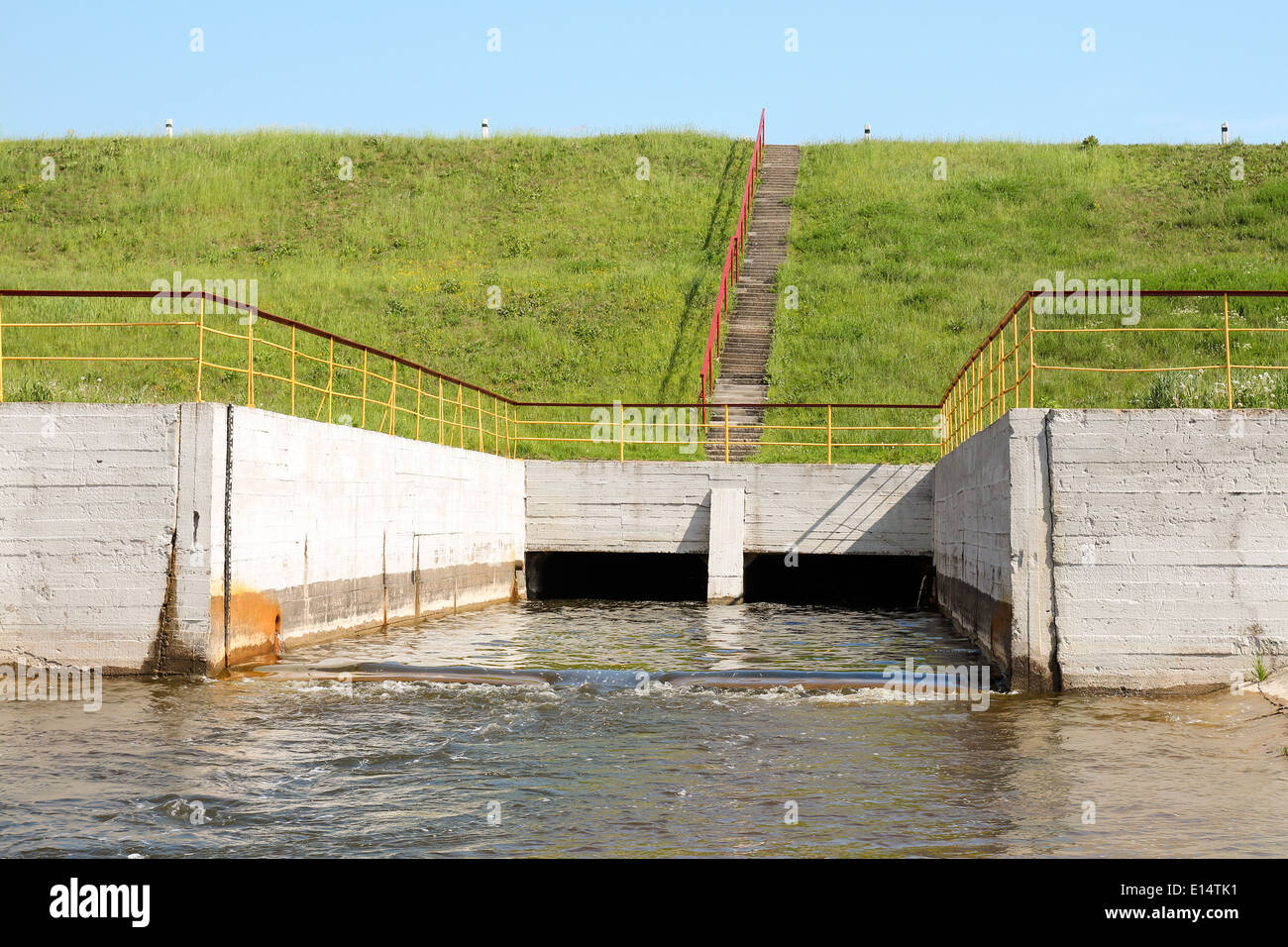 Water flowing over floodgates of a small dam Stock Photo - Alamy