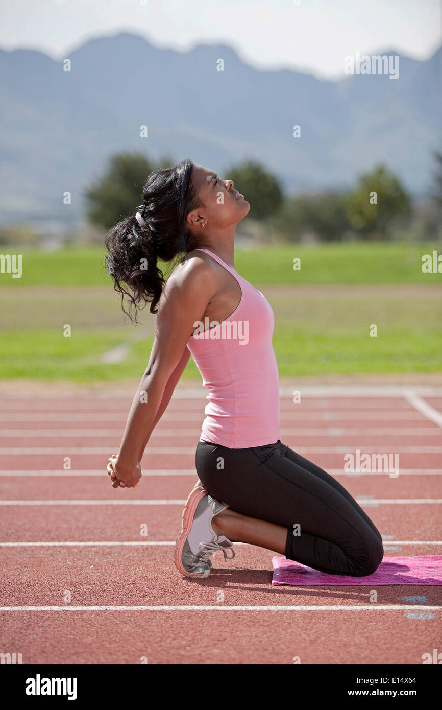 Sporty young woman on running track, stretching arms Stock Photo - Alamy