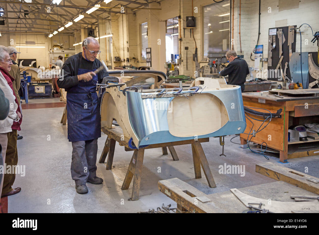 A panel beater adding an aluminum panel to a wooden ash frame of a car ...