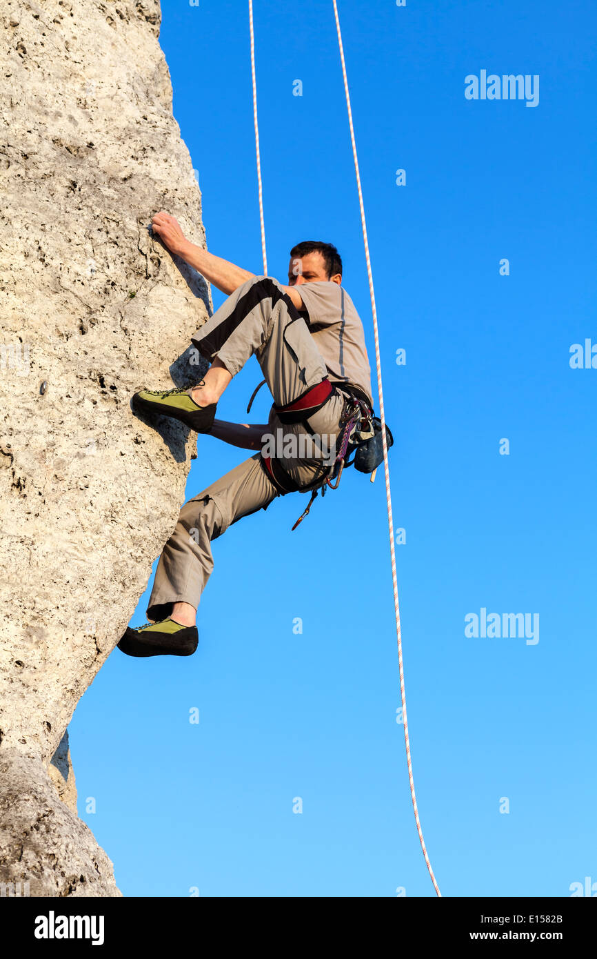 Difficult rock climbing position on horizontal cliff, mountains in ...