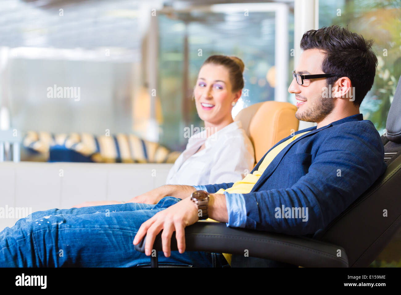 Young couple selecting together armchair in furniture store Stock Photo ...
