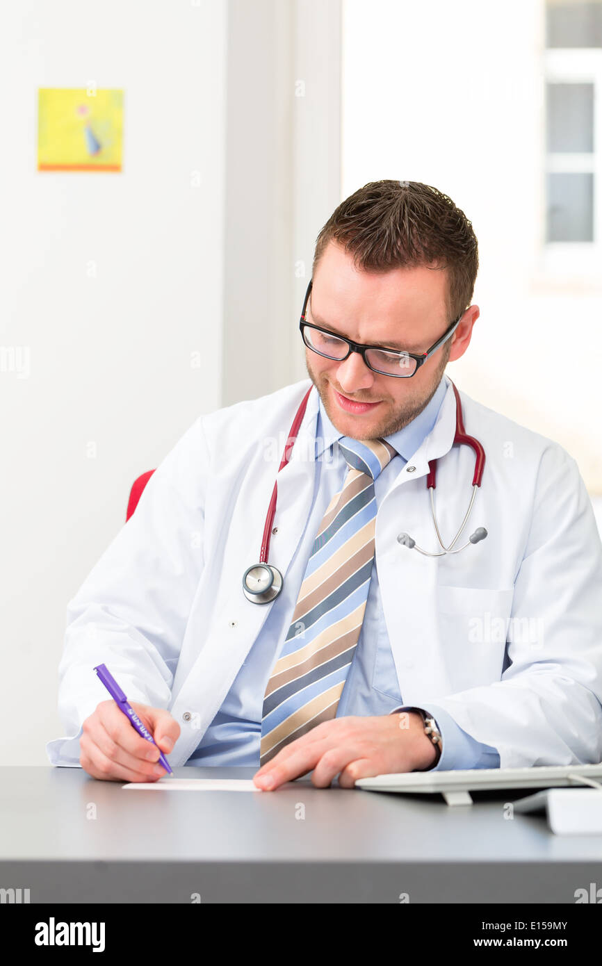 Young doctor writing medical prescription in surgery at desk Stock ...