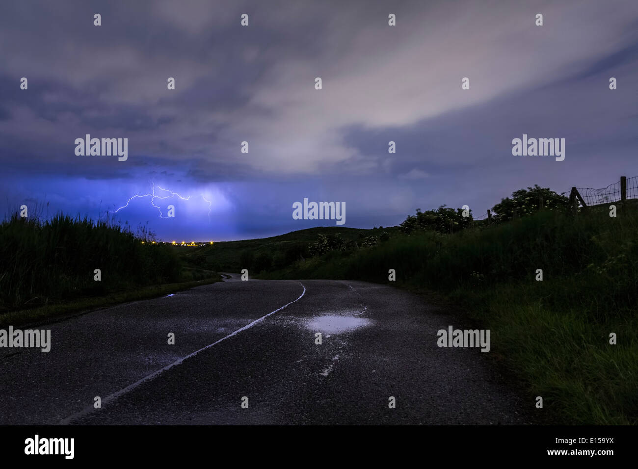 A road leads to a storm raging behind the hills Stock Photo - Alamy