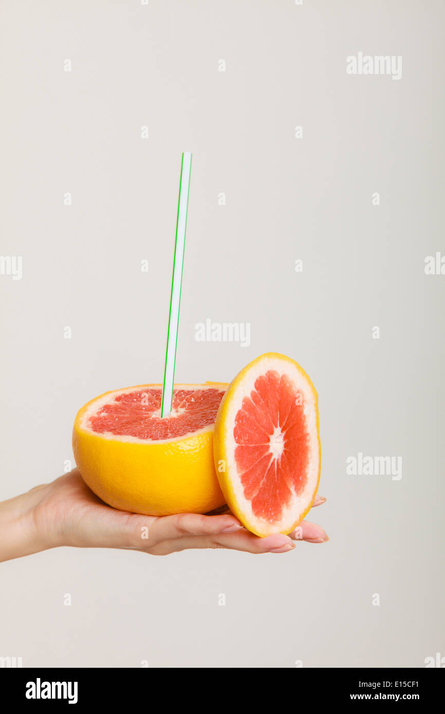 Summer vacation. Grapefruit citrus fruit with drinking straw in female ...
