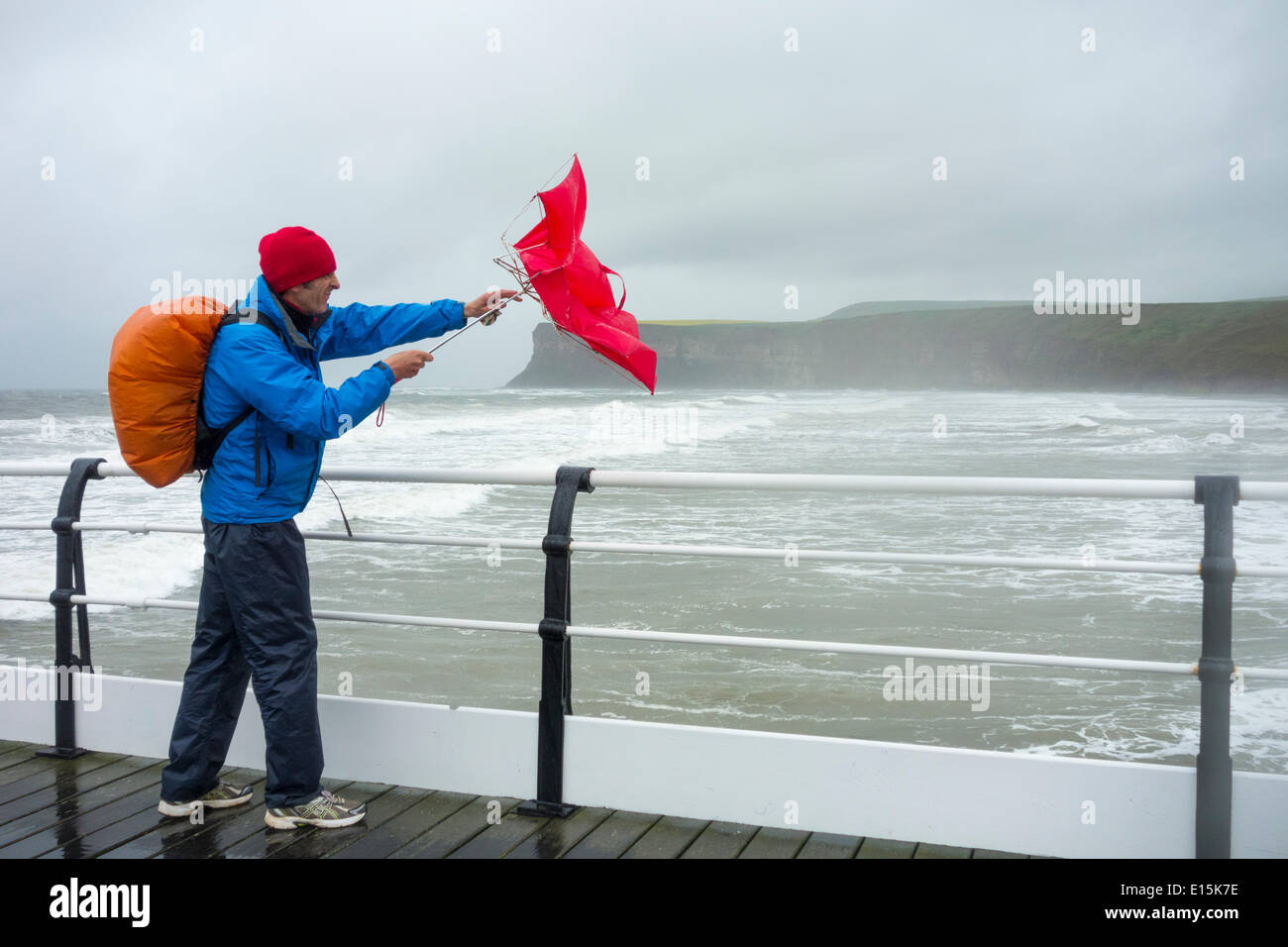Hiker walking The Cleveland Way struggling with umbrella on Saltburn ...