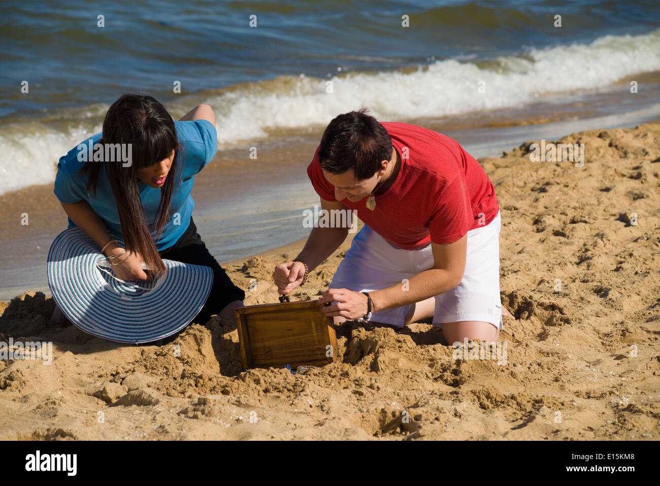 Couple discovering a treasure on the beach, a concept Stock Photo - Alamy