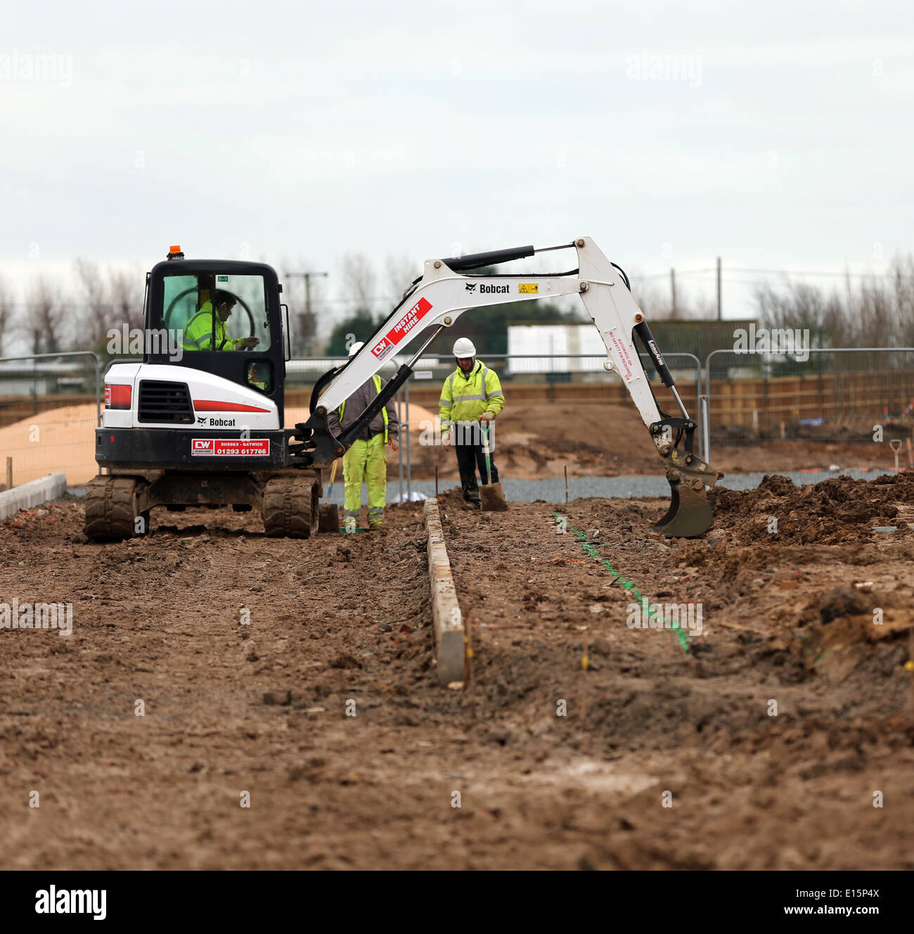 Tradesman workman on a building site in a digger excavating groundwork ...