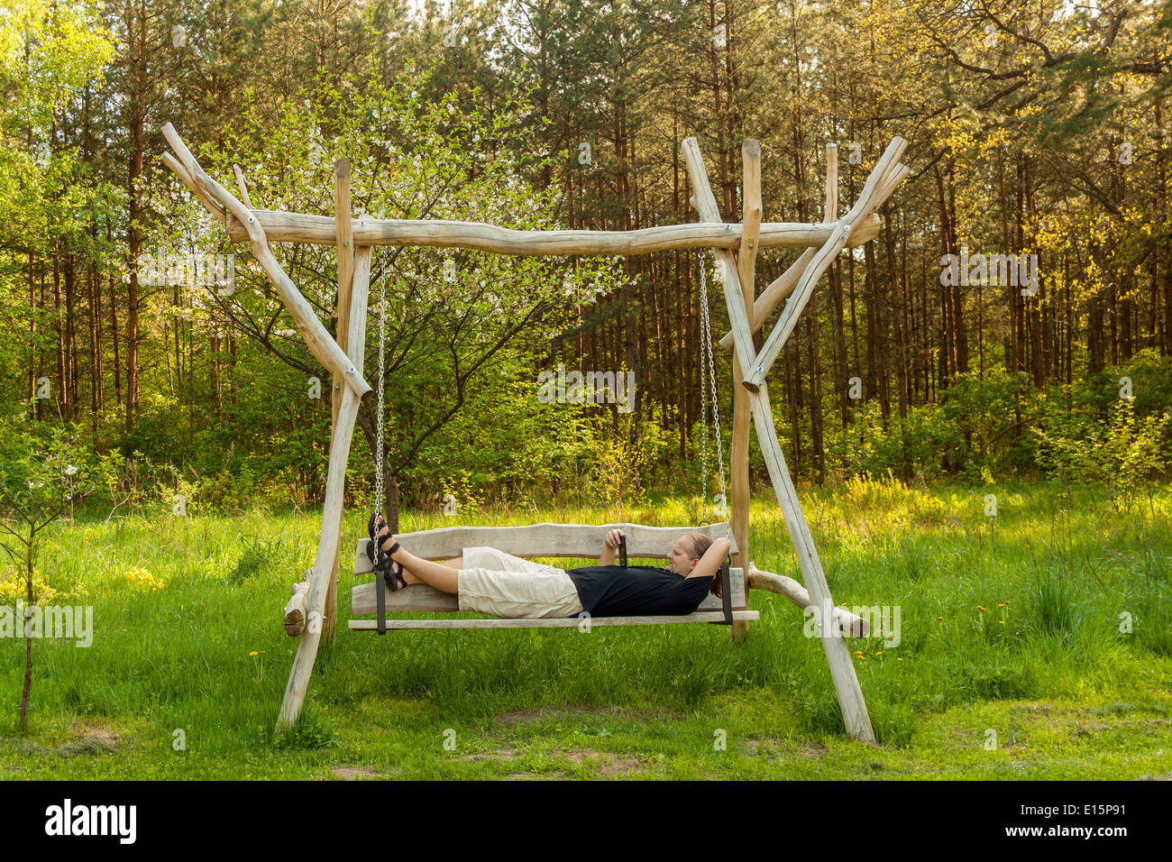 Adult man reading an ebook why lying on a swing Stock Photo - Alamy