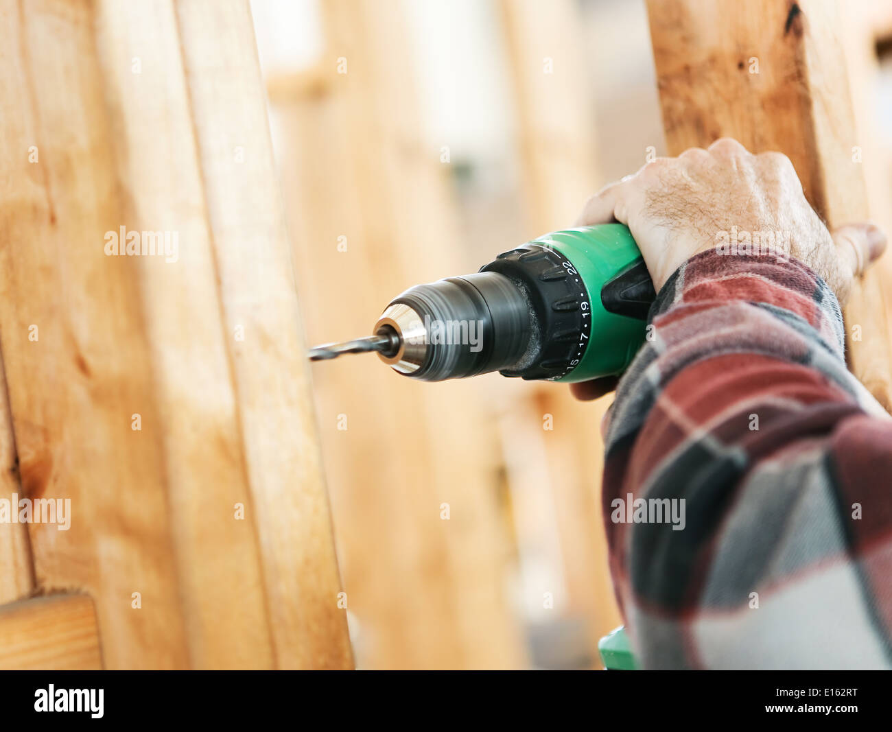 Closeup of a carpenter's hands using a drill on a construction site ...