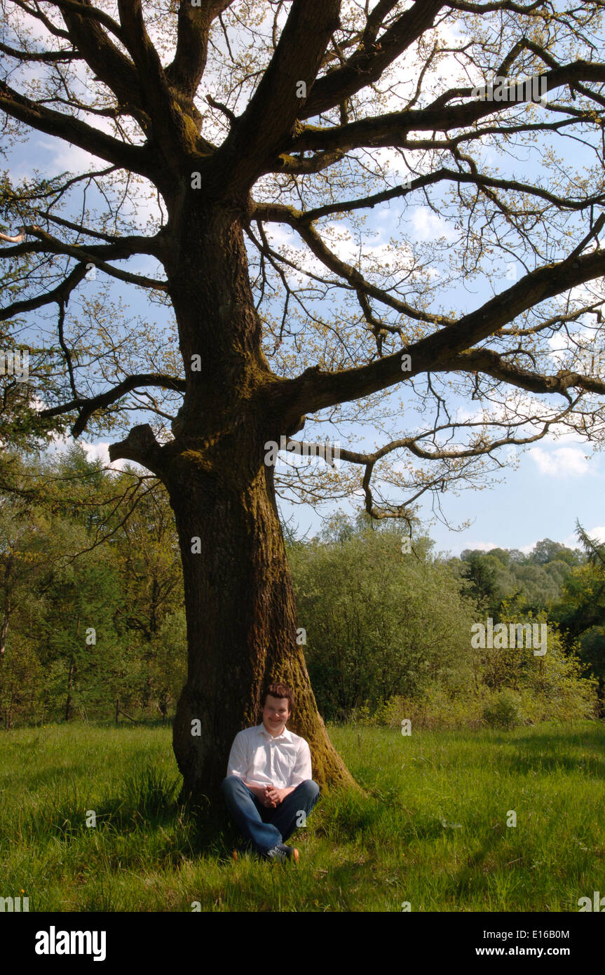 A Male Teenager Sitting Under A Tree Stock Photo - Alamy