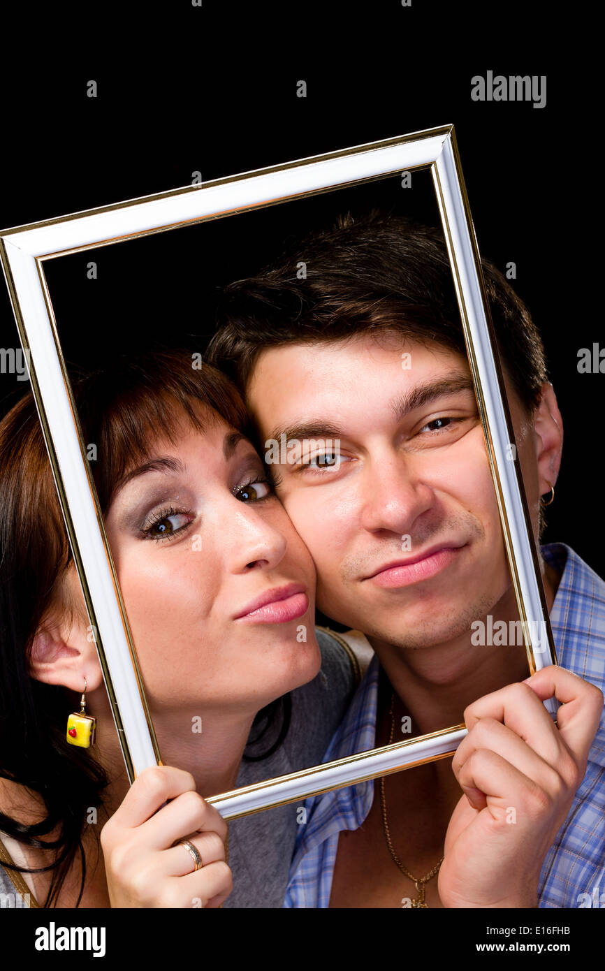 Happy couple in frame. Beautiful young couple looking through a picture ...