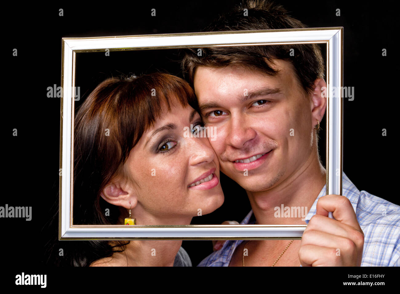 Happy couple in frame. Beautiful young couple looking through a picture ...