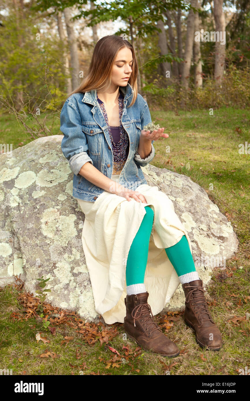 Young woman sitting on large stone Stock Photo - Alamy