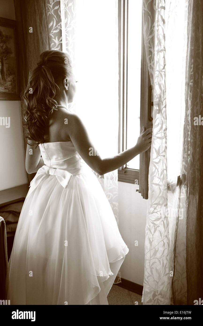 Bride looking through window Stock Photo - Alamy