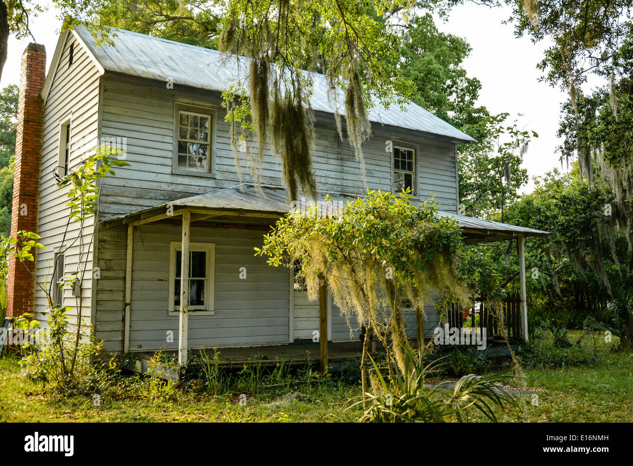 Creepy old abandoned house in disrepair in a Southern location with spanish moss on trees in ...