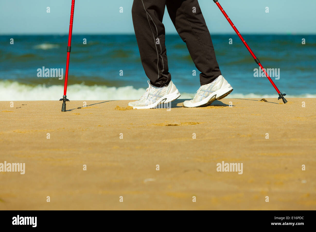 Nordic walking. Closeup of female legs hiking on the beach. Active and ...
