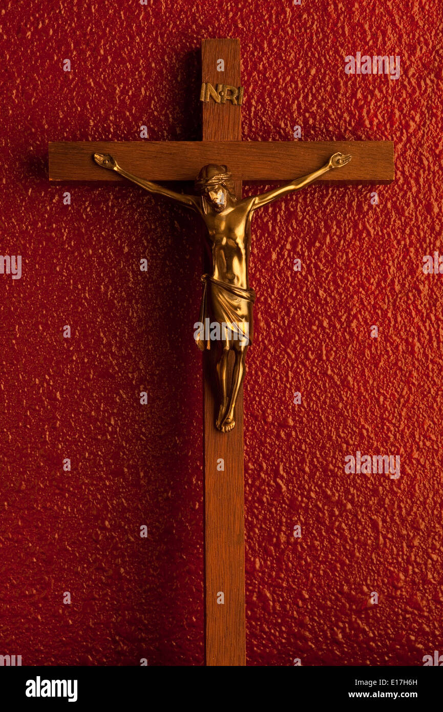 Jesus crucified on cross against red wall Stock Photo - Alamy