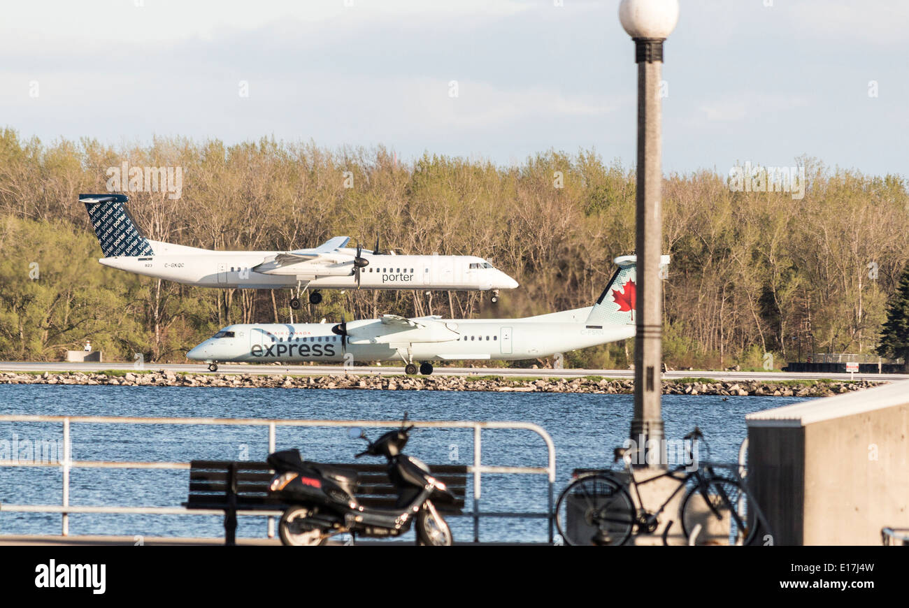 Porter plane landing flies over an Air Canada plane ready to take off ...
