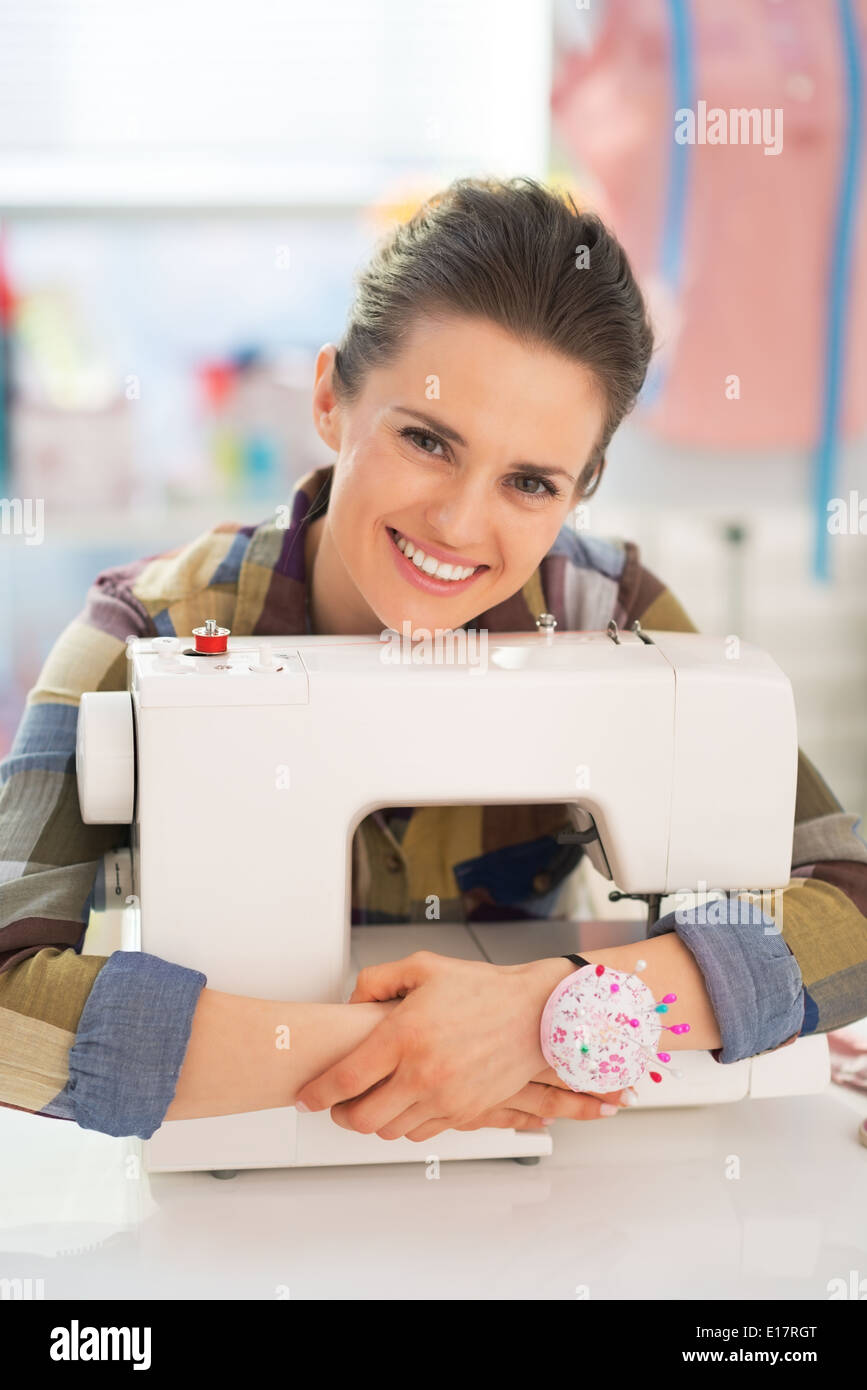 Happy seamstress embracing sewing machine Stock Photo - Alamy
