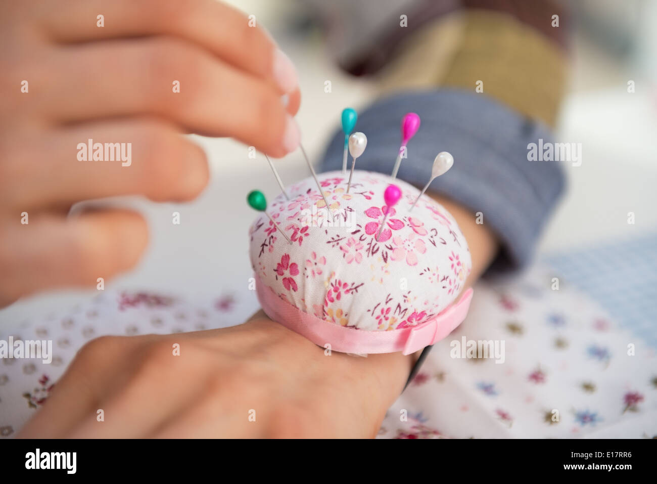 Closeup on seamstress putting needle in pincushion Stock Photo - Alamy