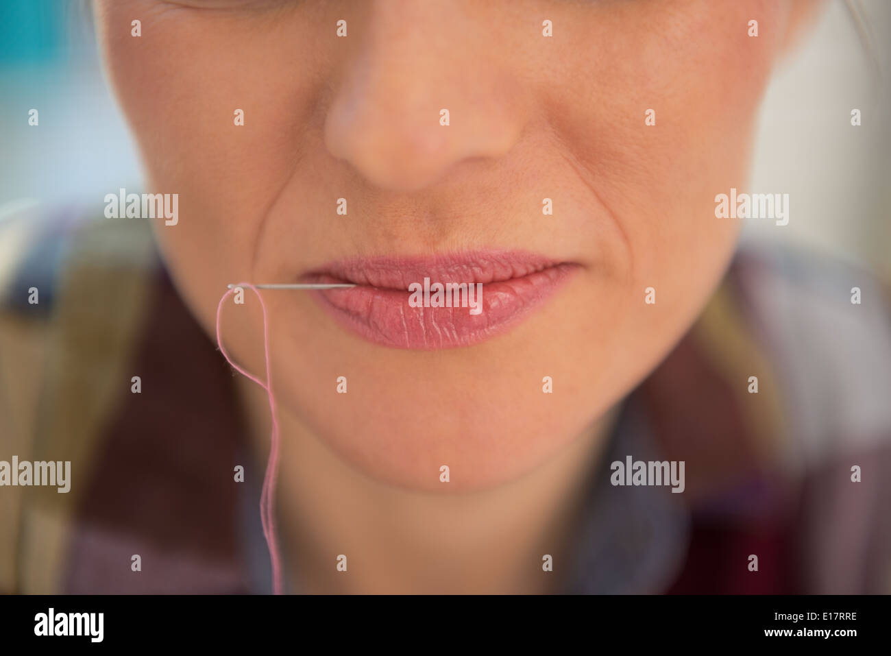 Closeup on seamstress with needle in lips Stock Photo - Alamy