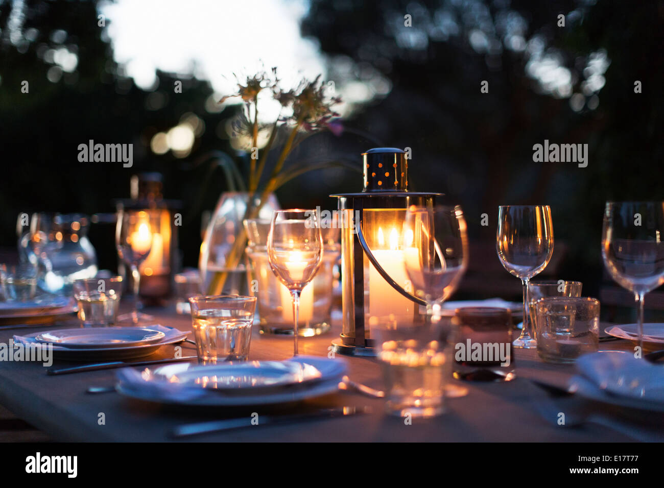 Candles in lanterns on patio dining table with place settings Stock ...