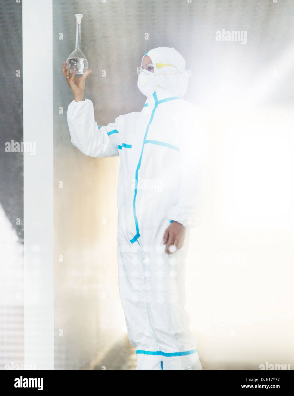Scientist in clean suit examining liquid in beaker Stock Photo - Alamy