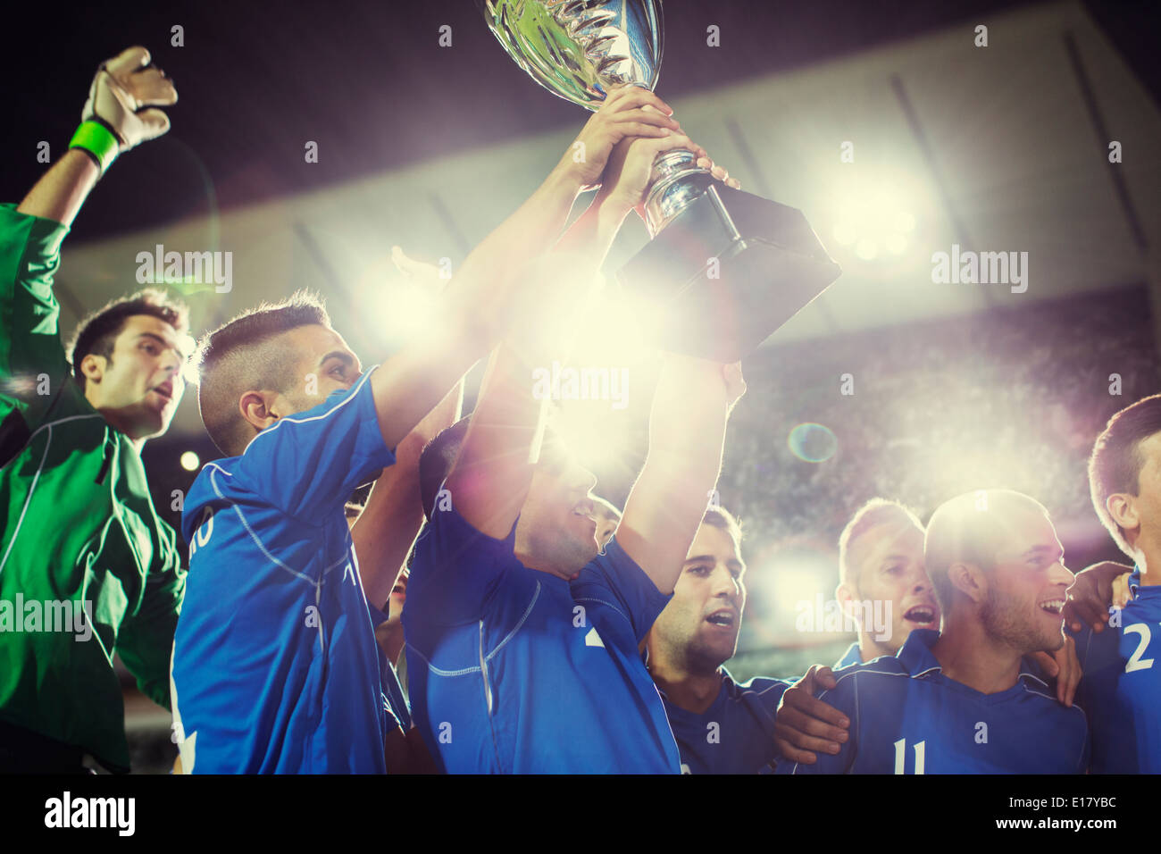Soccer team celebrating with trophy on field Stock Photo - Alamy