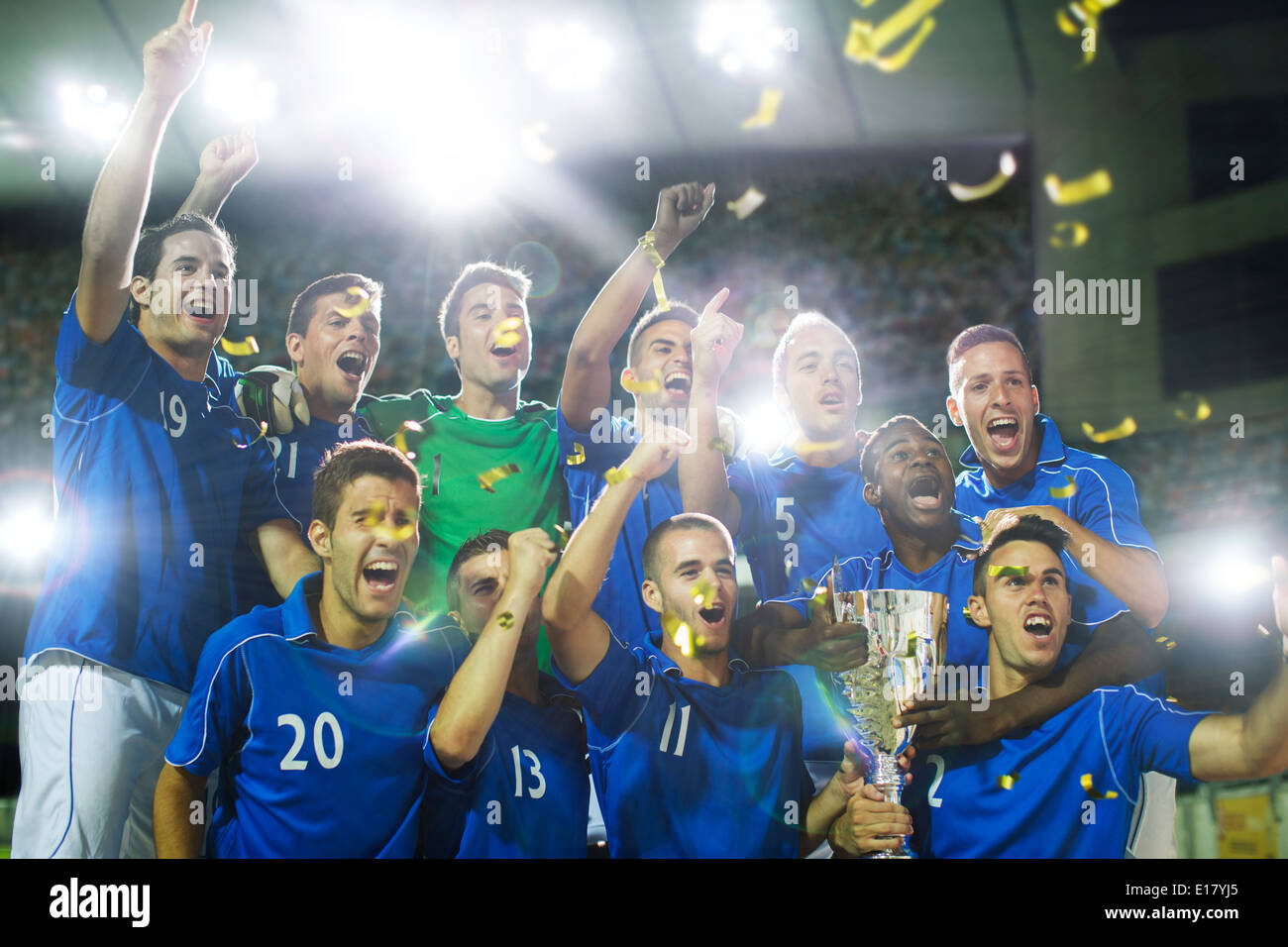 Soccer team celebrating with trophy on field Stock Photo - Alamy