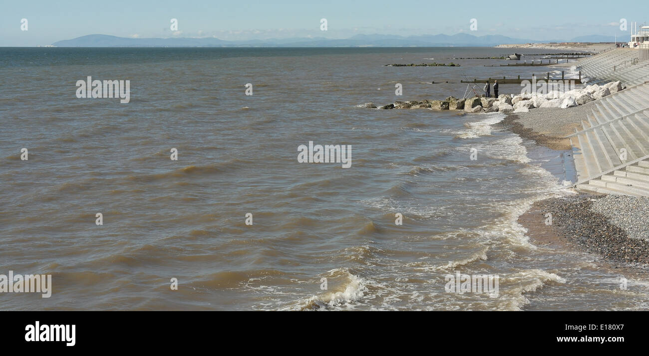 Blue sky high tide view, to Cumbrian Mountains, 3 fishermen standing ...