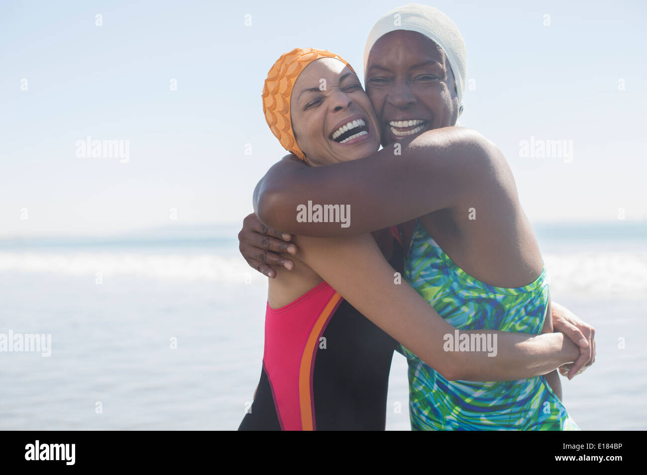 Enthusiastic women hugging in bathing suits and caps Stock Photo - Alamy