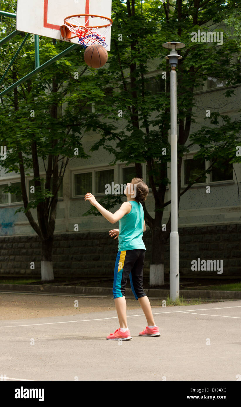 Young athletic teenage girl playing basketball practicing on her own as ...