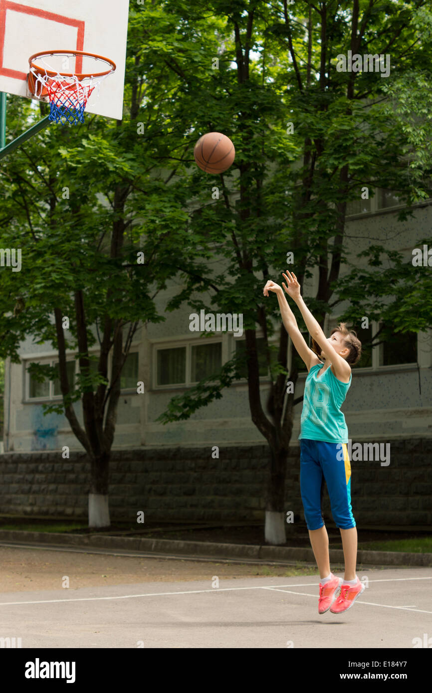 Teenage girl playing basketball shooting the ball at the hoop as she ...