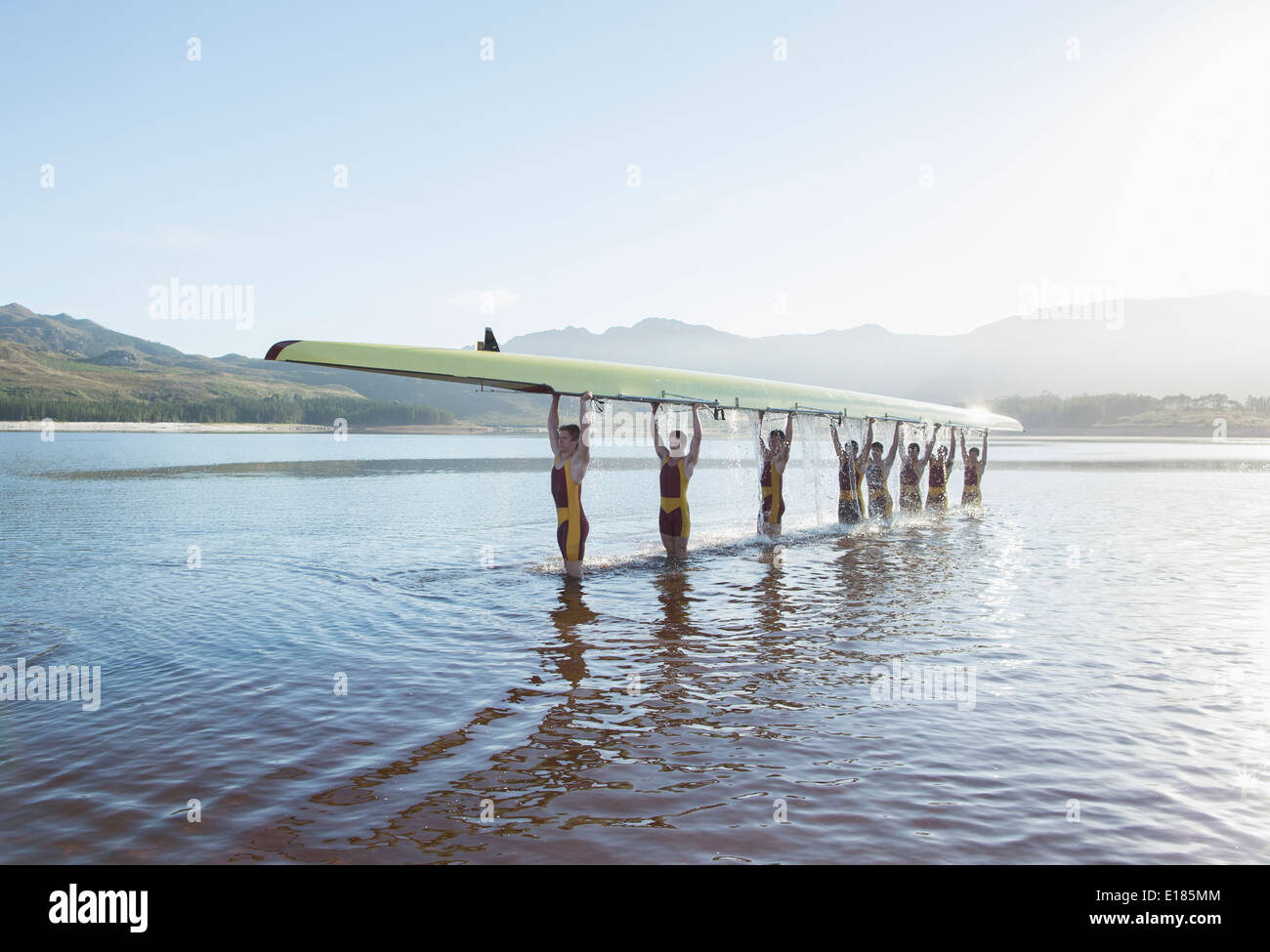 Rowing team holding scull overhead in lake Stock Photo - Alamy