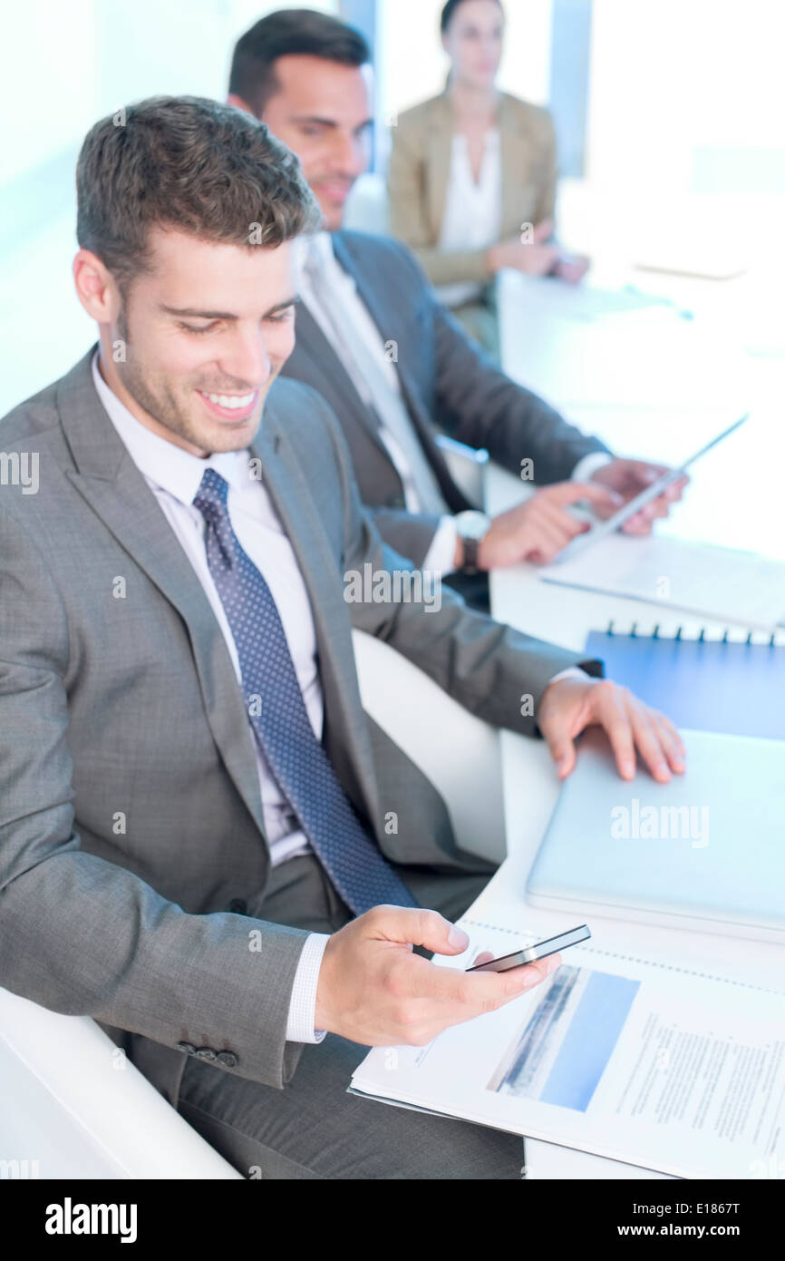 Businessman texting with cell phone in conference room Stock Photo - Alamy