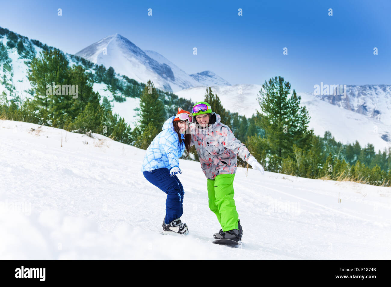 Two friends standing on snowboards balancing Stock Photo - Alamy