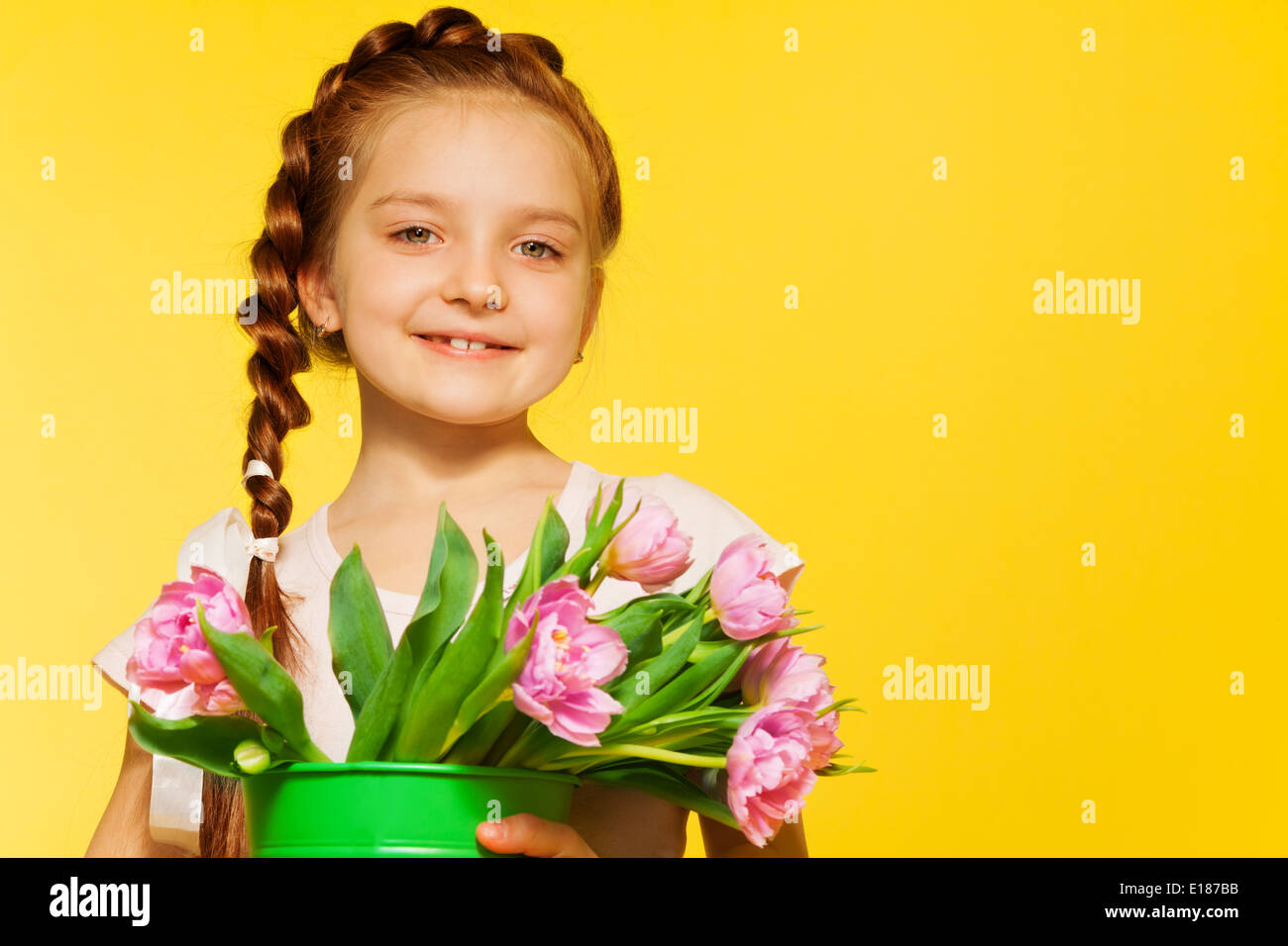 Cute small girl holding pail with pink tulips Stock Photo - Alamy