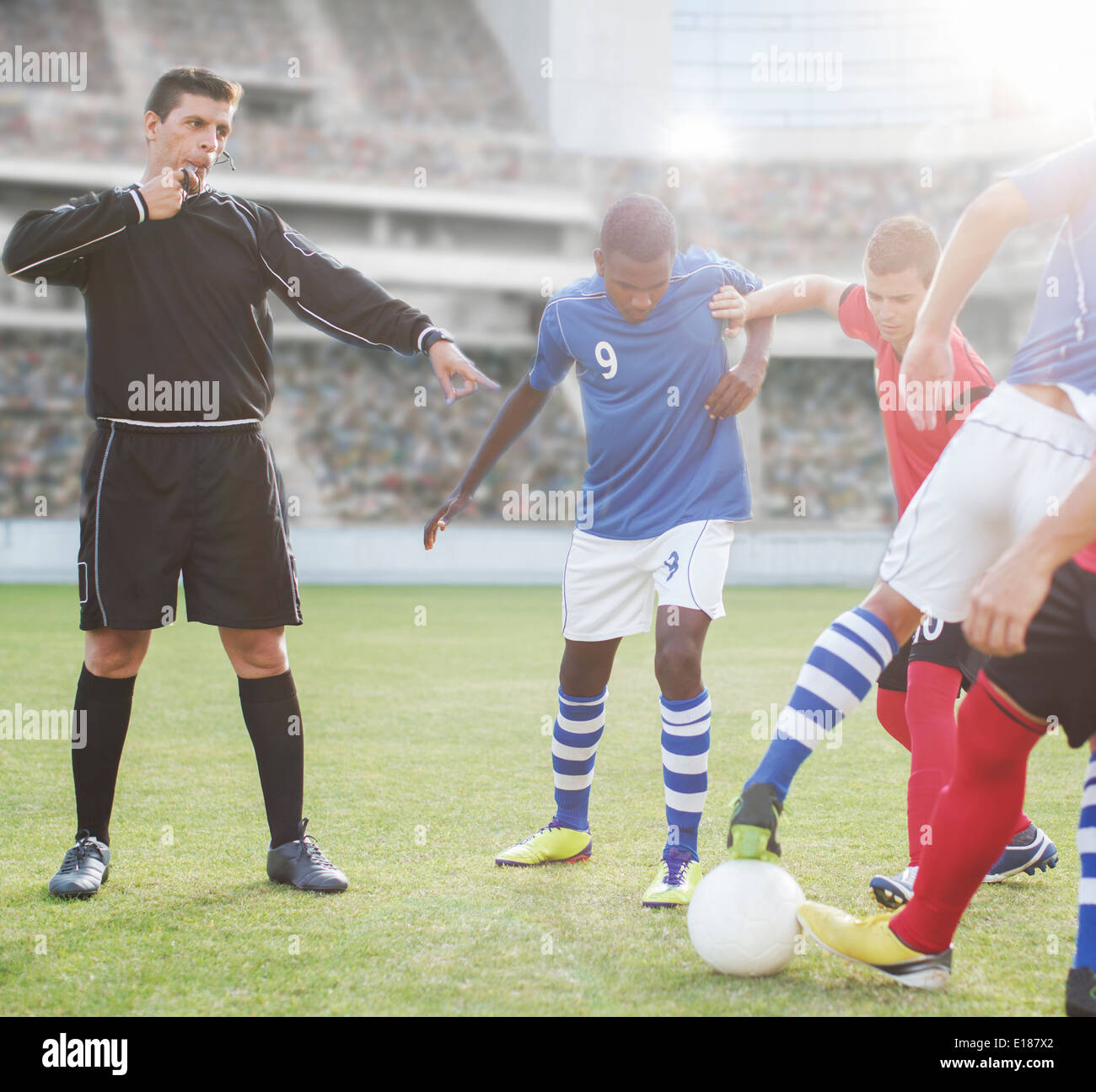 Referee whistling at soccer players on field Stock Photo - Alamy
